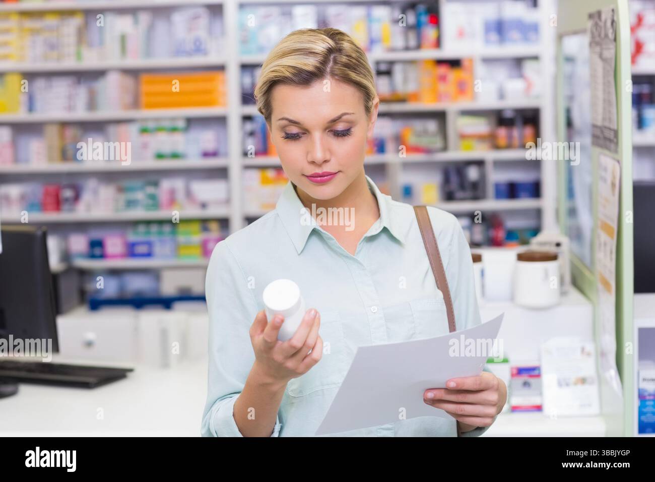 Woman standing at pharmacy counter, reading prescription sheet and ...
