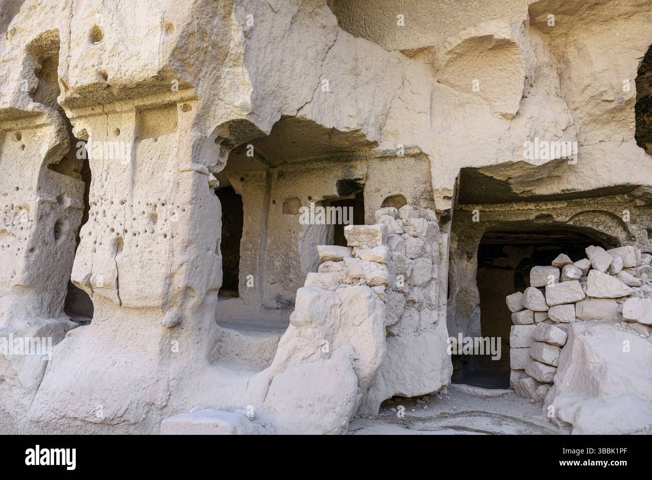 A cluster of interconnected cave rooms and stone entrances is carved in ...