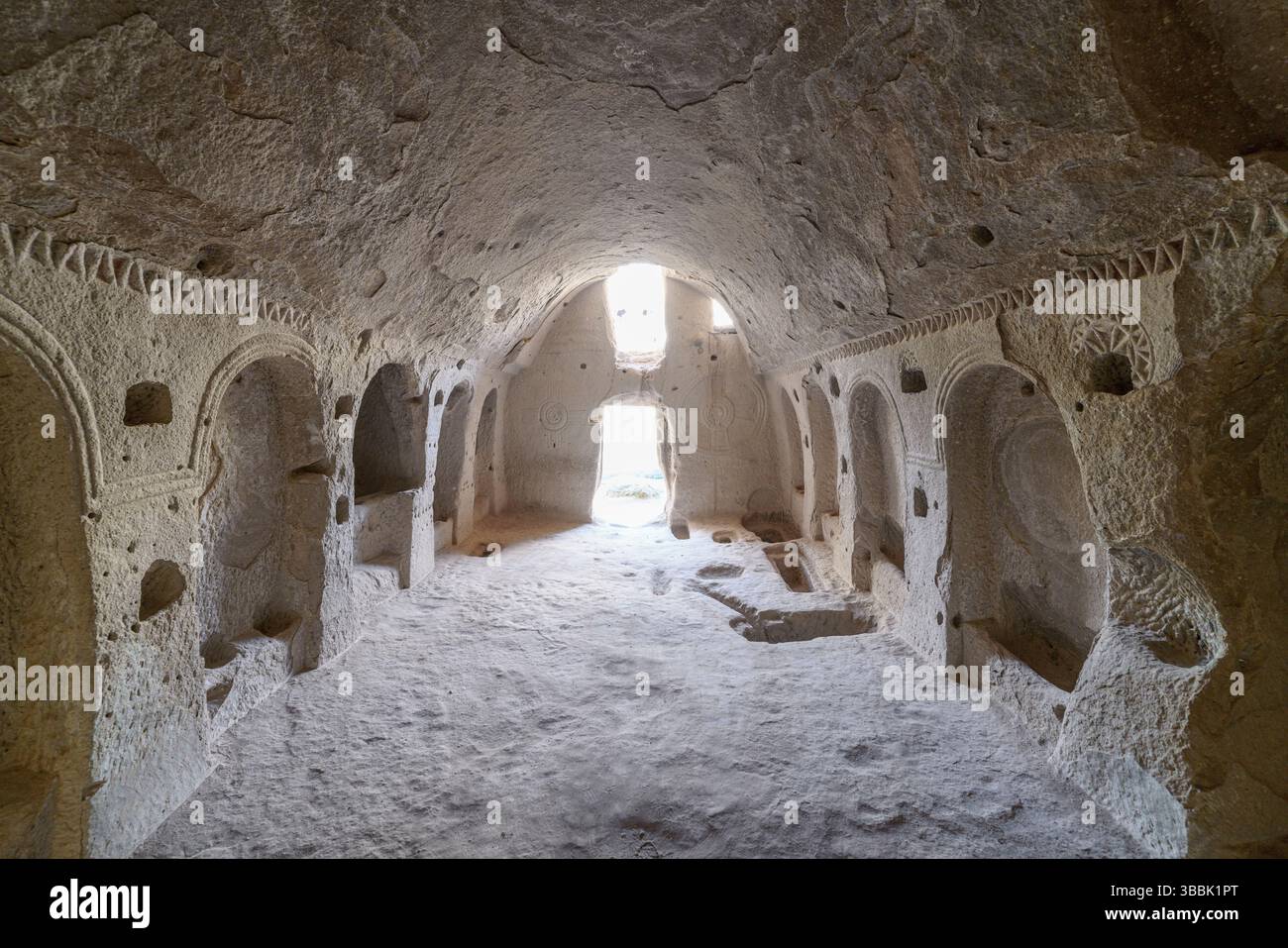 A large single-nave cave church with arched ceiling and carved benches ...