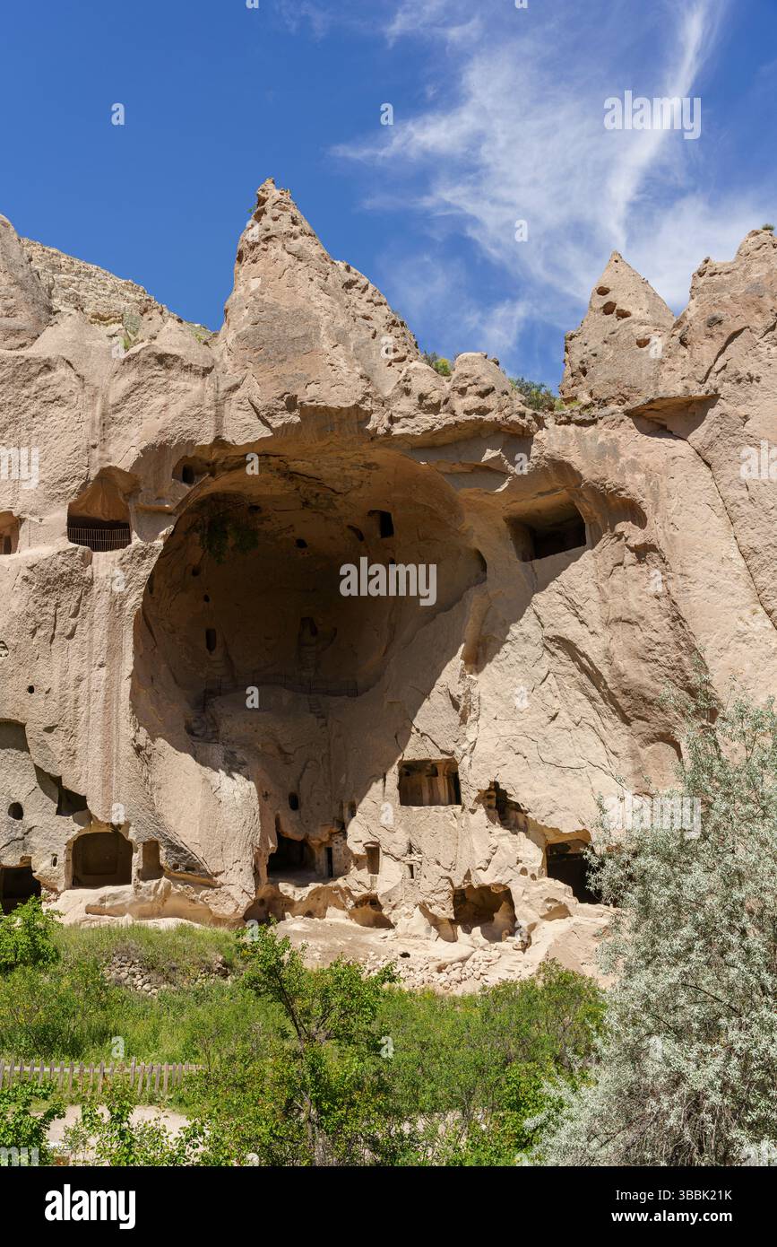 A large cave entrance with rounded arch and shadowed interior is carved ...