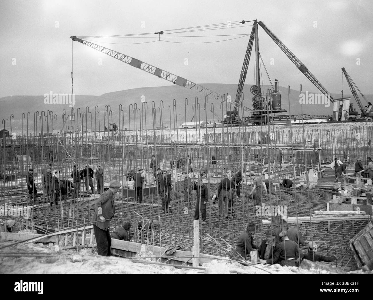 With a background of Welsh mountains workmen construct the foundations ...