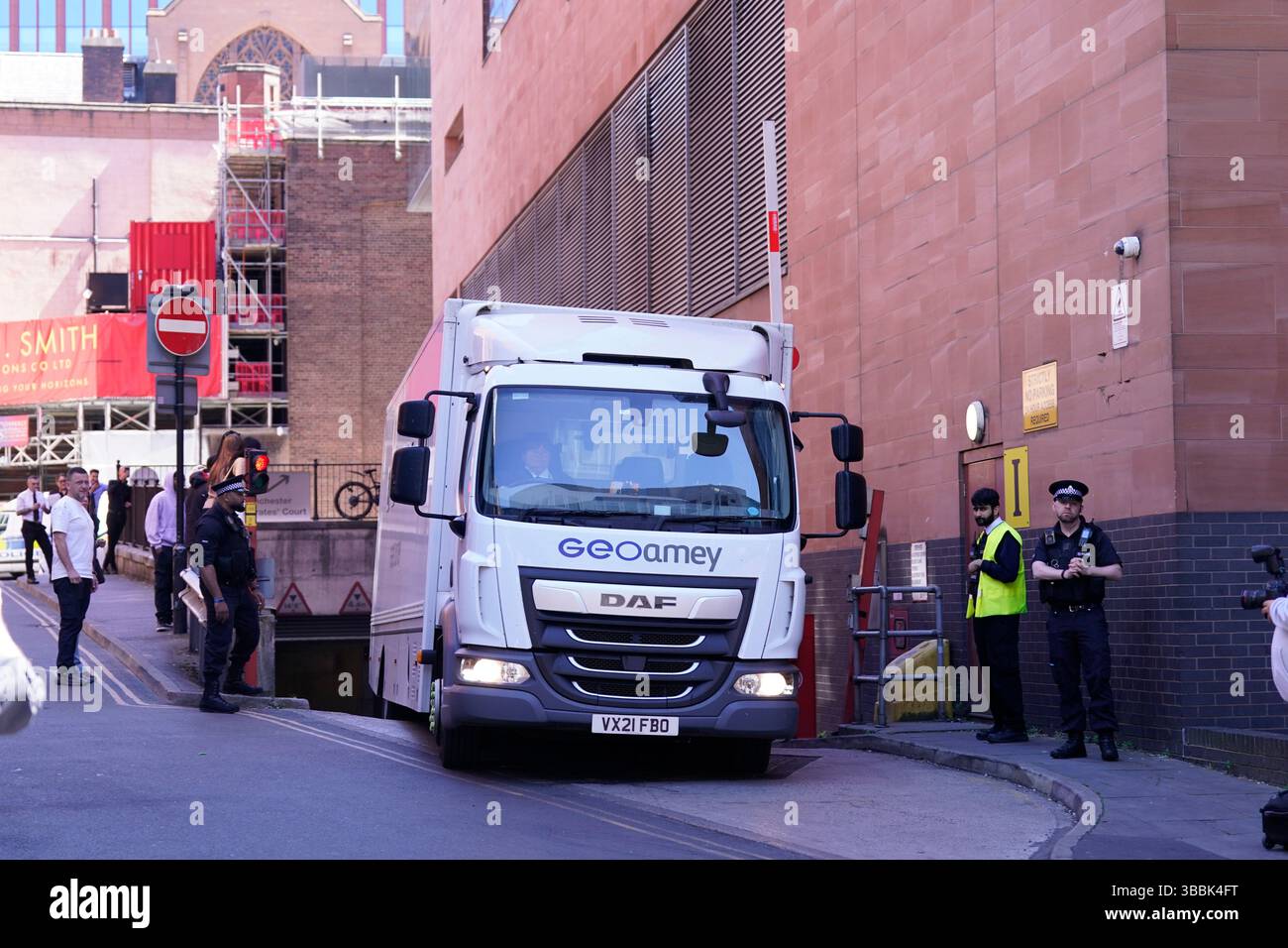 Police officers clear a pathway as a prison van leaves the rear ...
