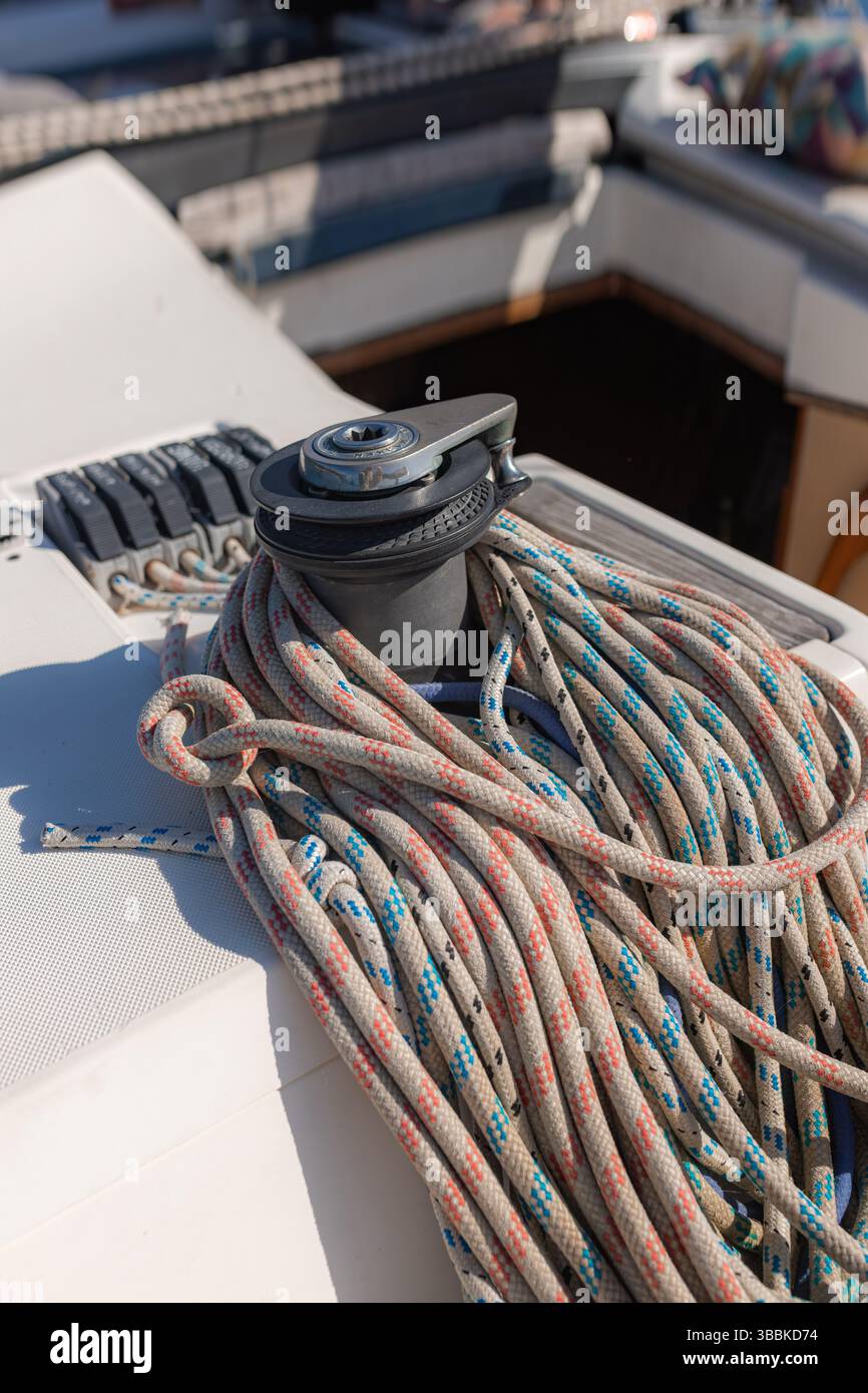 Close-up of multicolored sailing ropes neatly coiled around a winch on ...