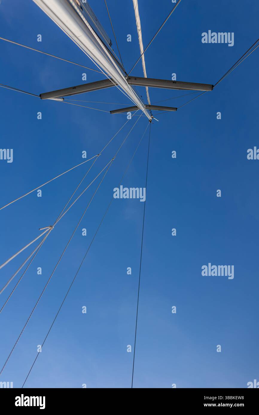 Yacht mast and ropes viewed from below against clear blue sky ...