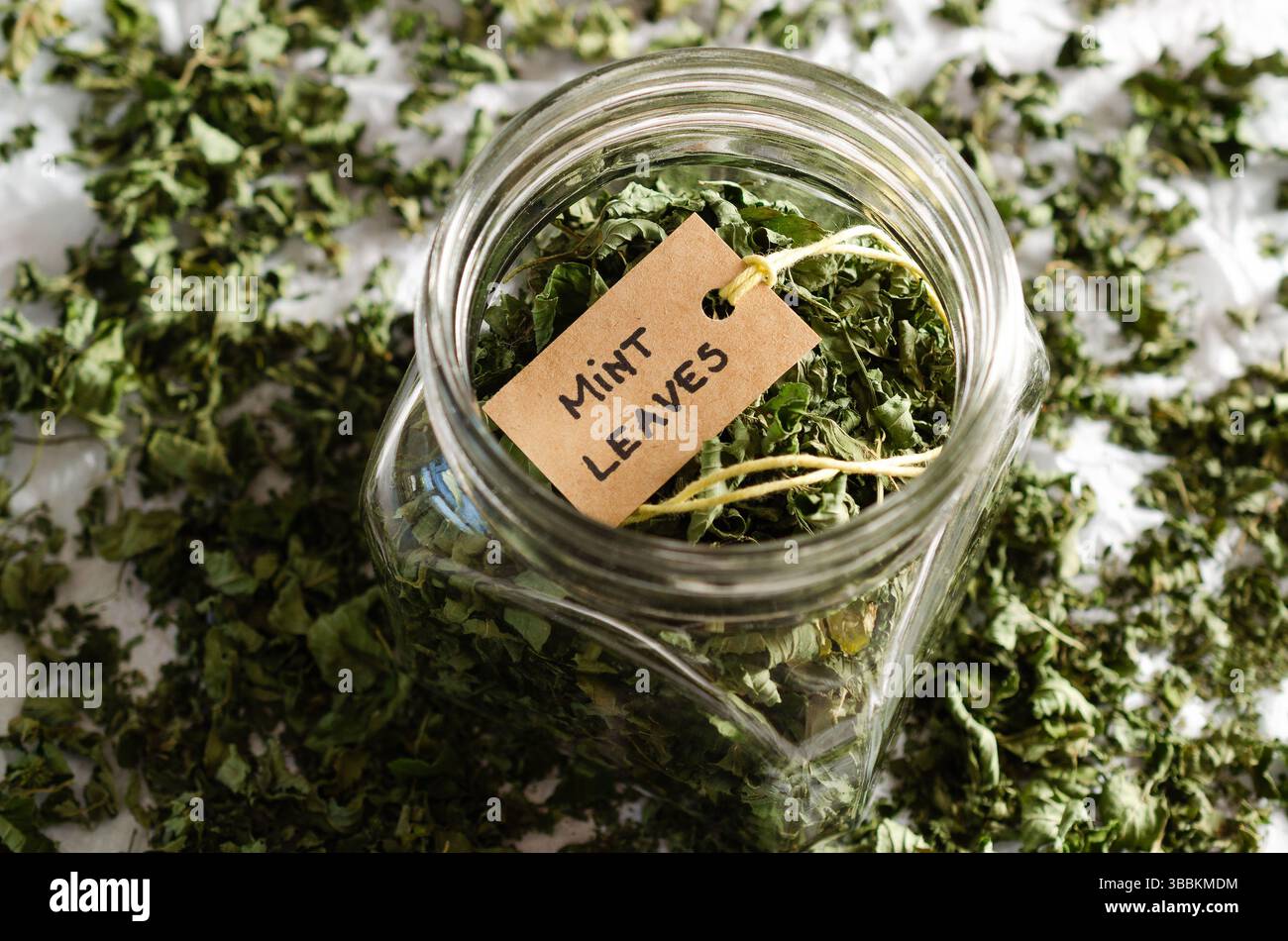 Dried mint leaves in a jar with a label made of recycled paper and on a ...