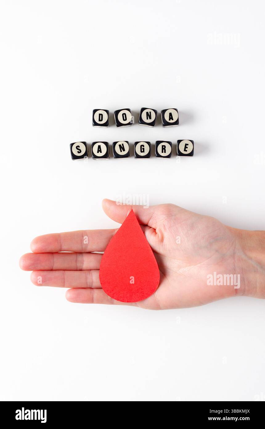 A female hand holding a paper drop of blood and a donate blood text in ...