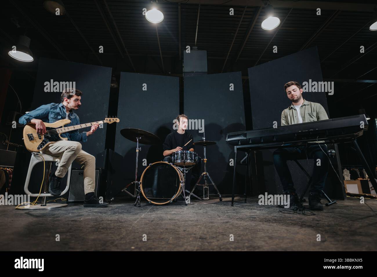 Band rehearsing in studio with bassist, drummer, and pianist performing ...