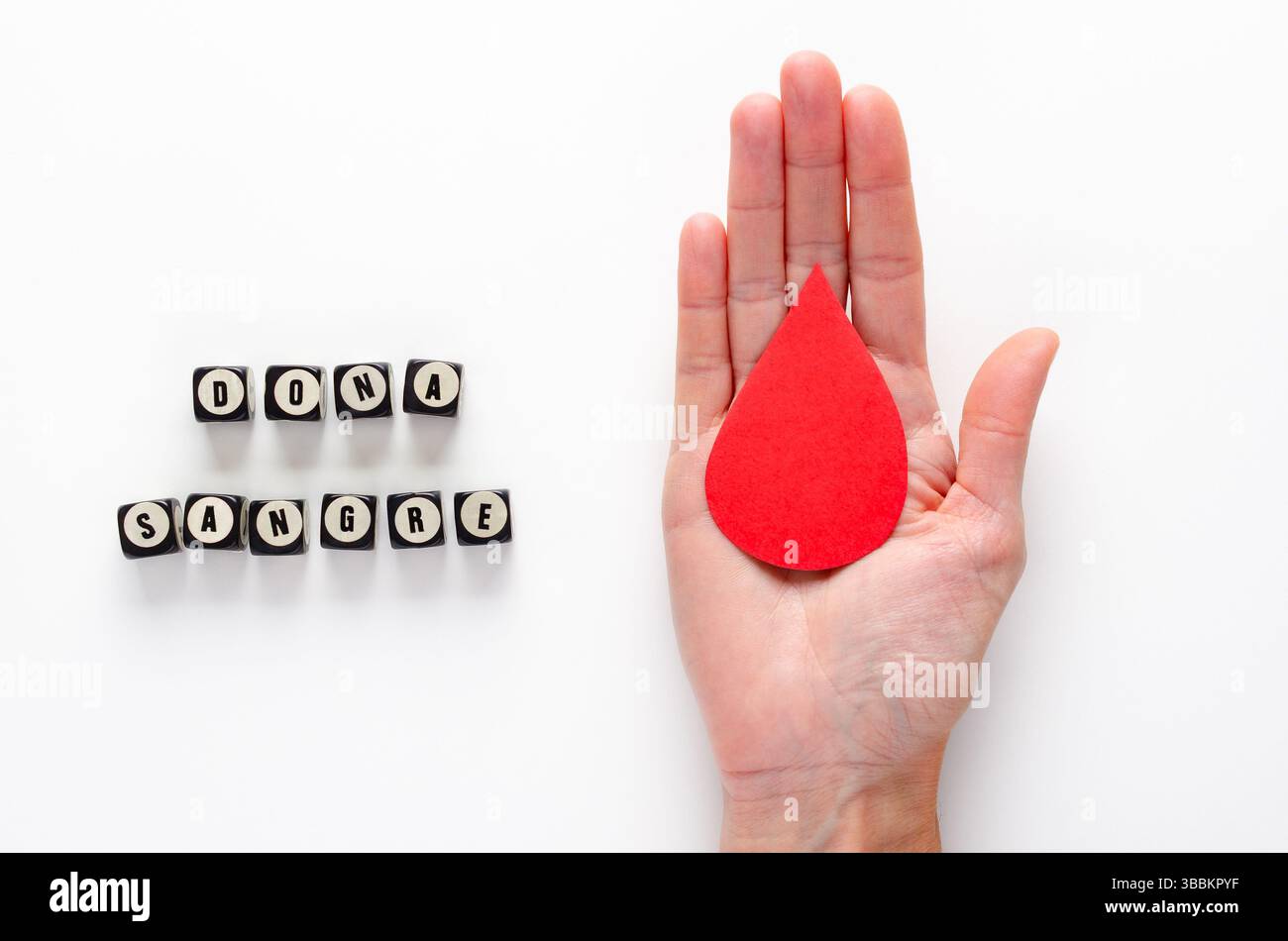 A female hand holding a paper drop of blood and a donate blood text in ...