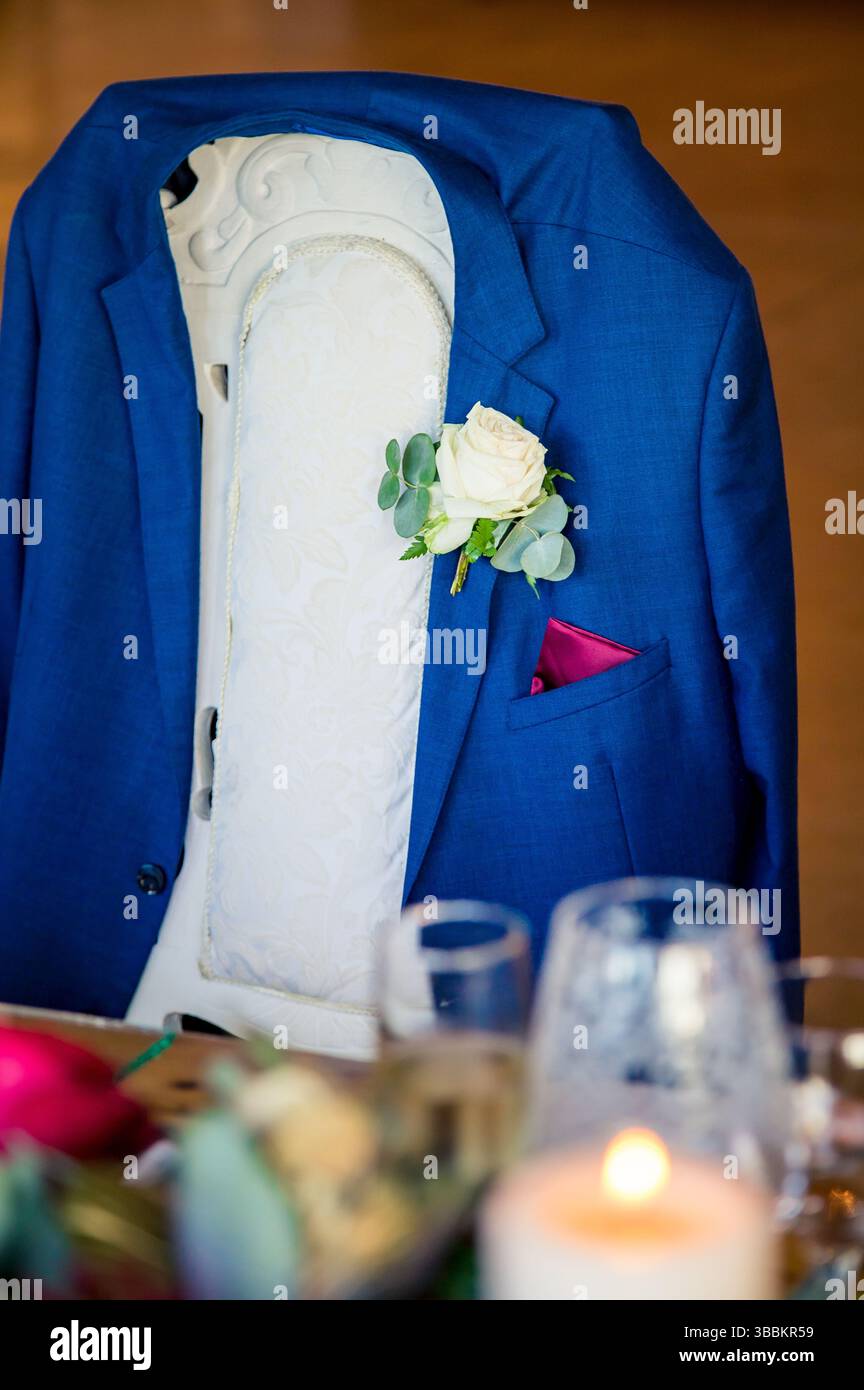 Grooms suit jacket hung over the back of a chair at the reception Stock ...