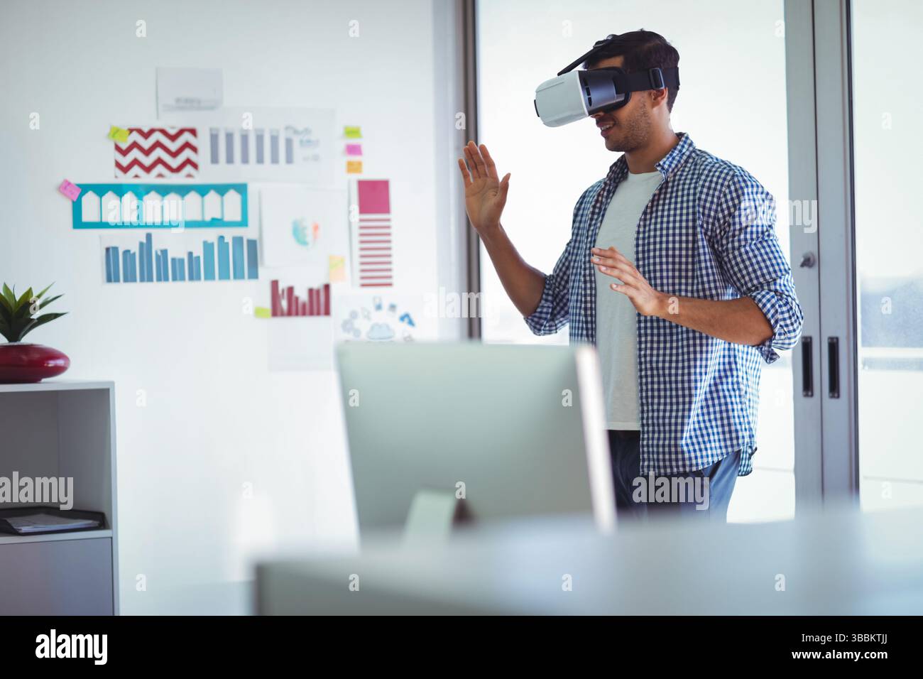 VR headset is resting on desk beside computer monitor in office, with ...