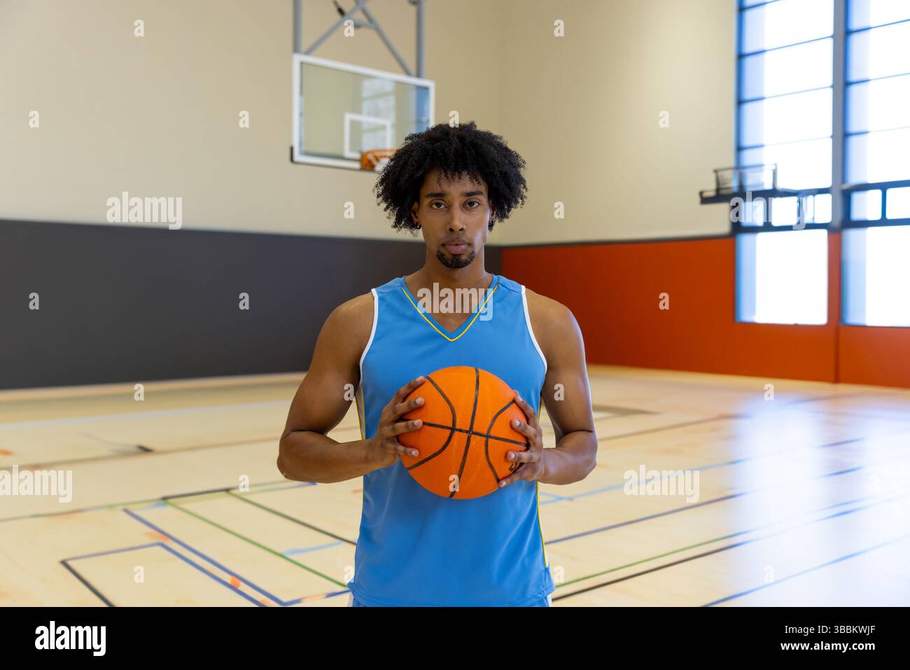 Young adult African American man holding orange basketball on indoor ...