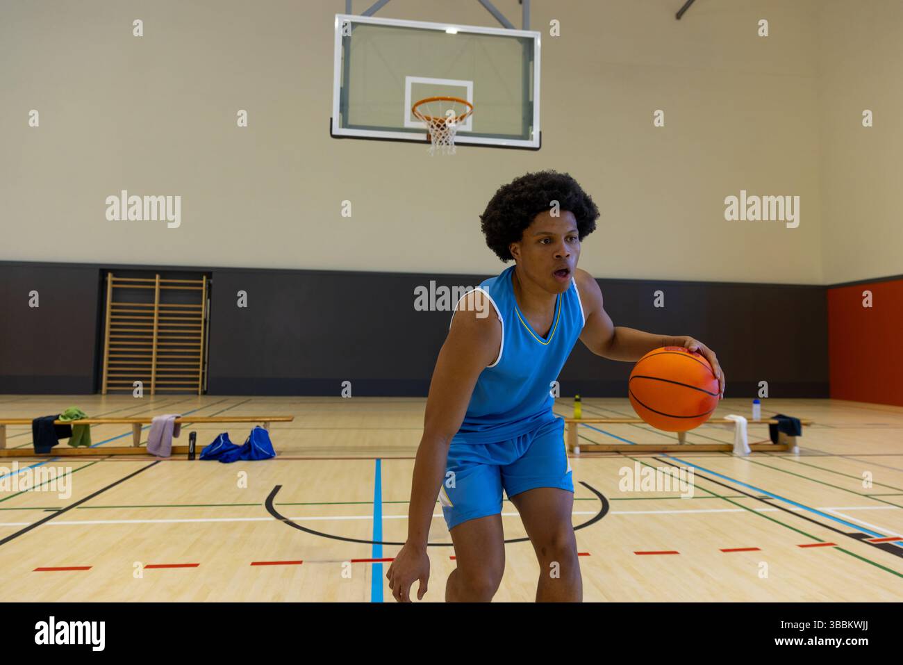African American male athlete dribbling basketball on gym court, with ...