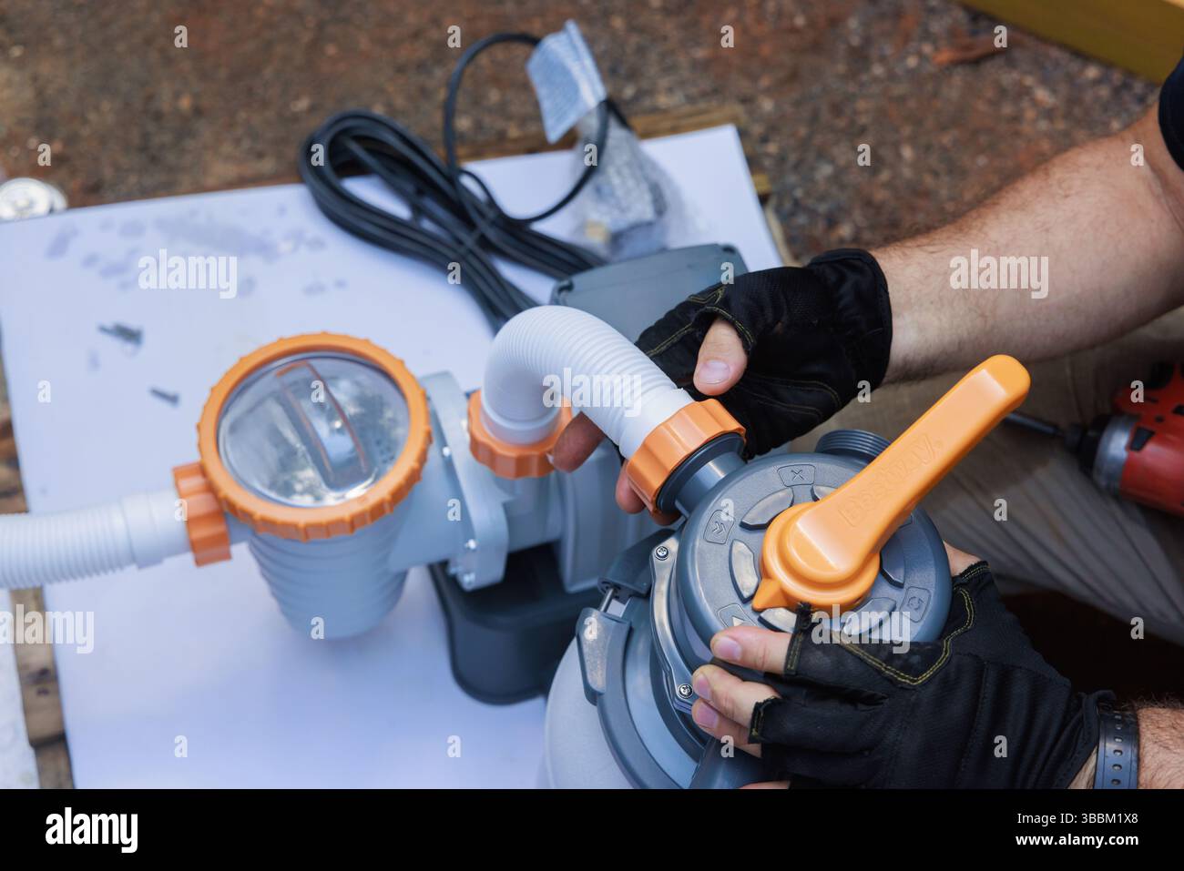 Individual is connecting parts of water pump to pool filter in outdoor ...