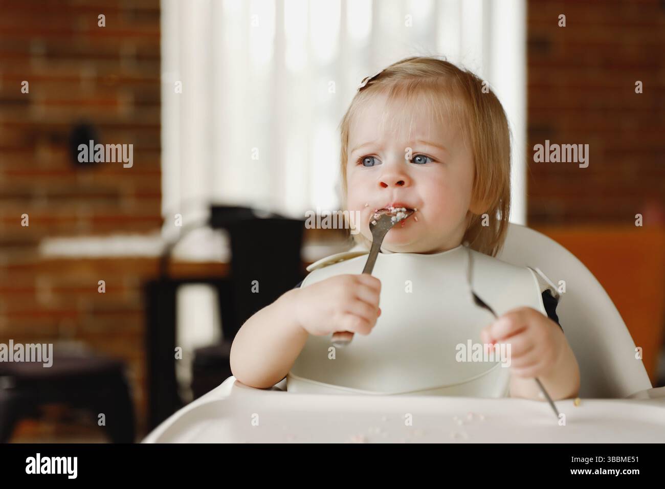 Cute 11 month infant girl or toddler sitting on high chair at feeding ...