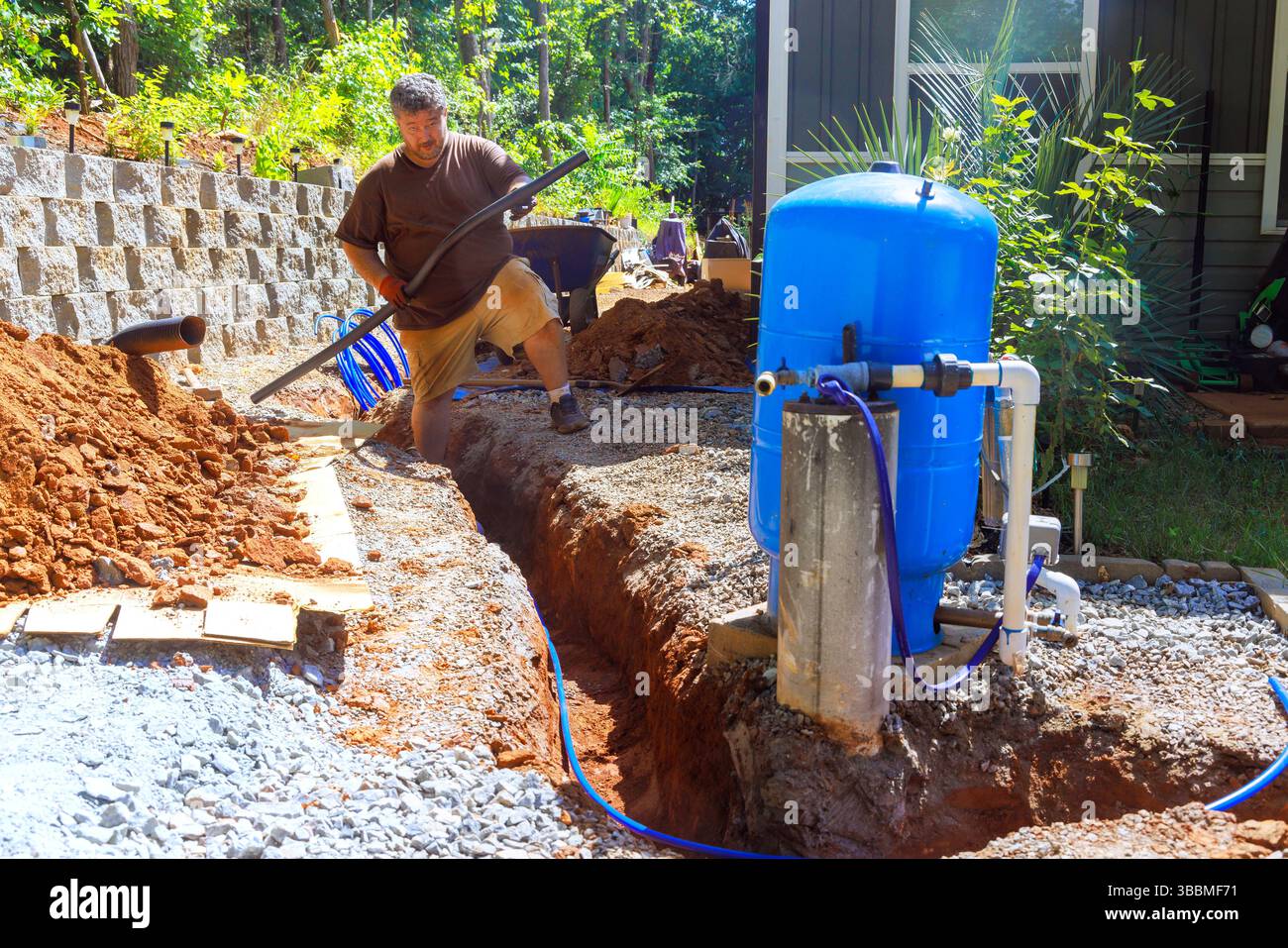 Worker actively pipe PEX laying to trench for artesian water well ...