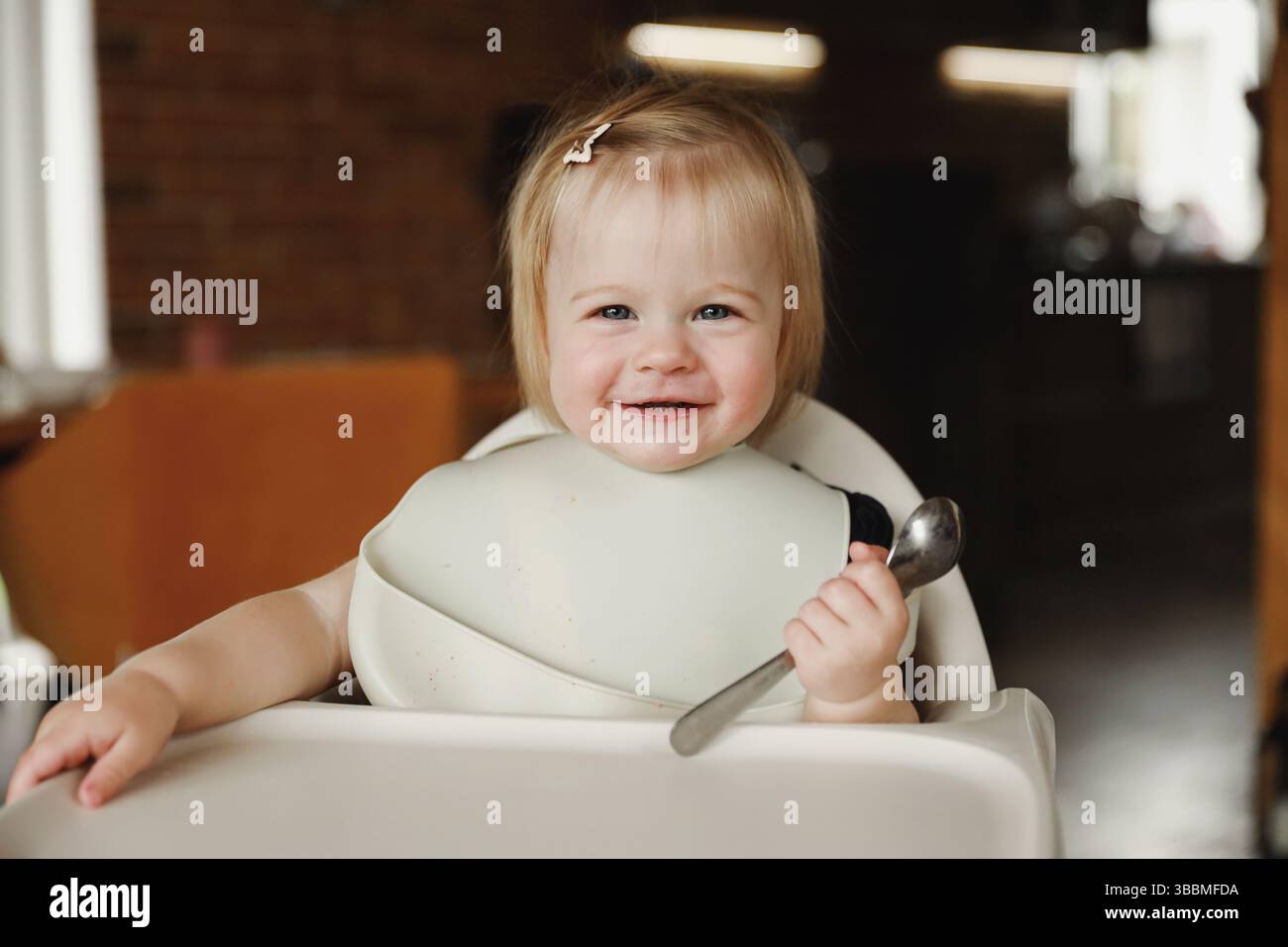 Adorable smiling infant girl or toddler sitting on high chair at ...