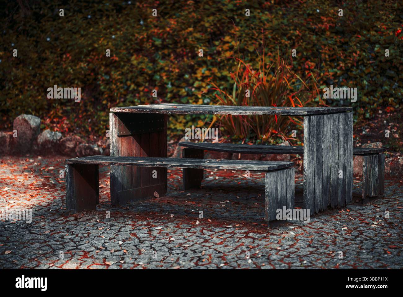 Weathered wooden picnic table and benches on a cobblestone ground ...