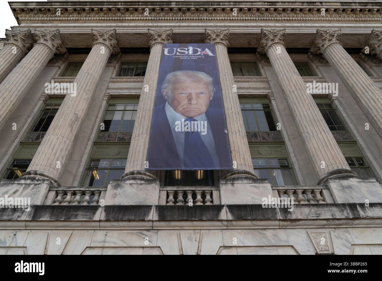 A banner with a photograph of President Donald Trump hangs near the ...