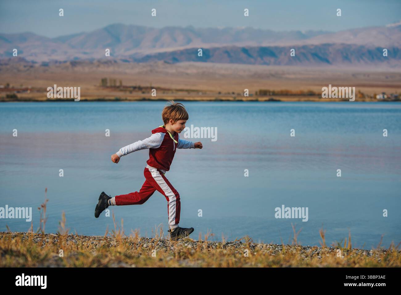 Active boy running on the lake shore Stock Photo - Alamy