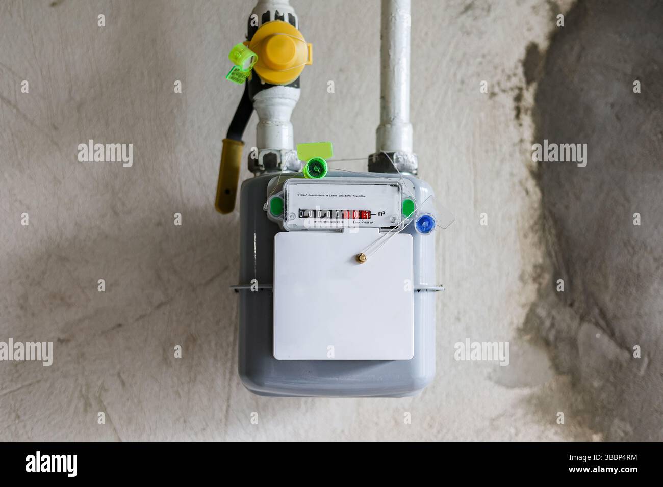 Gas meter and pipes, on concrete wall in a house under renewal. Indoor ...