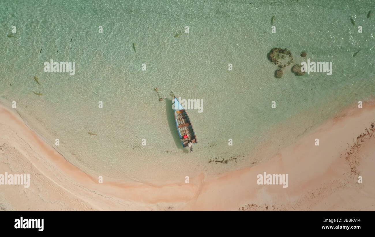 Aerial view of a lonely boat anchored near a pink sand beach in ...