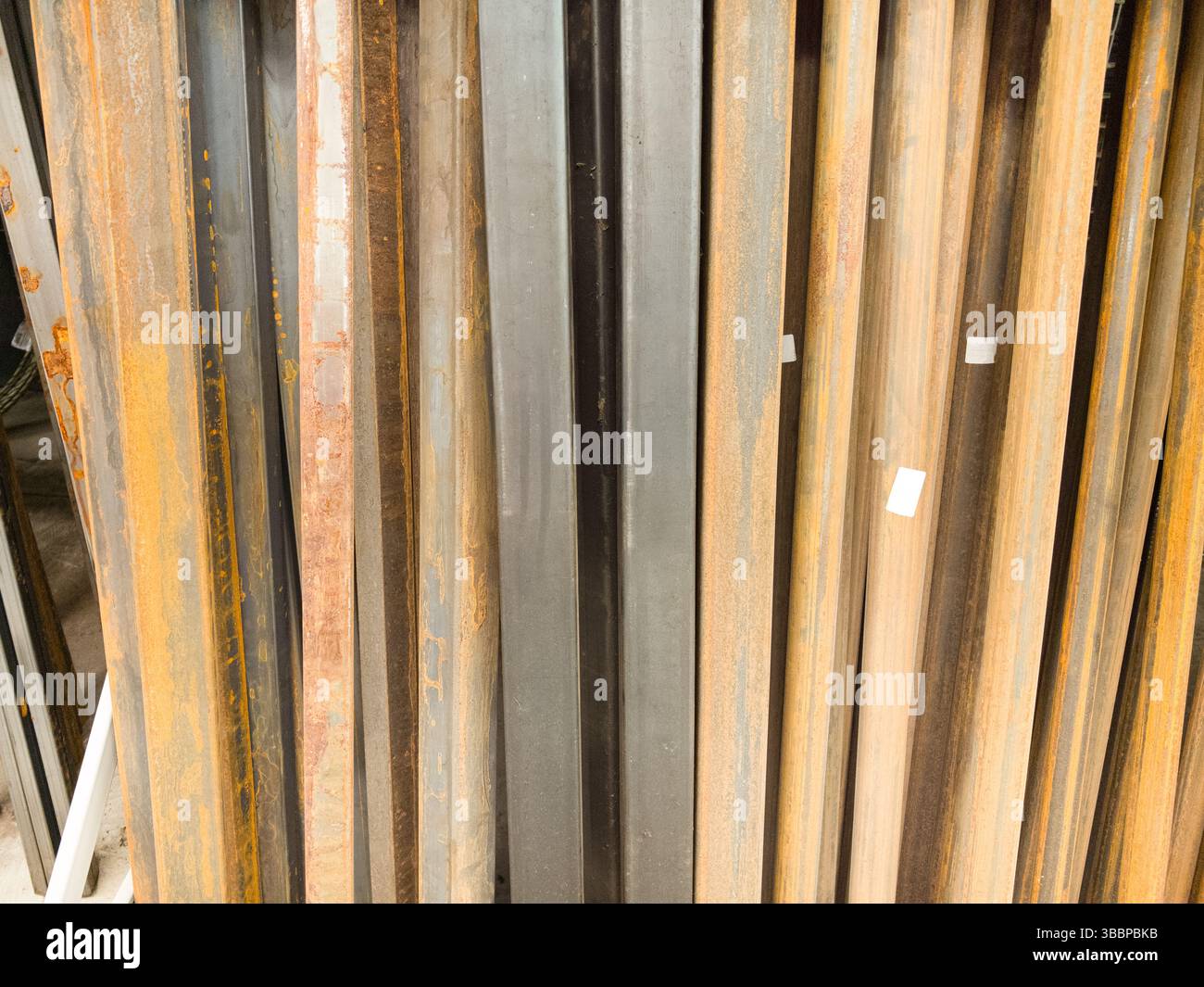 A collection of metal bars is neatly stacked in a spacious warehouse ...