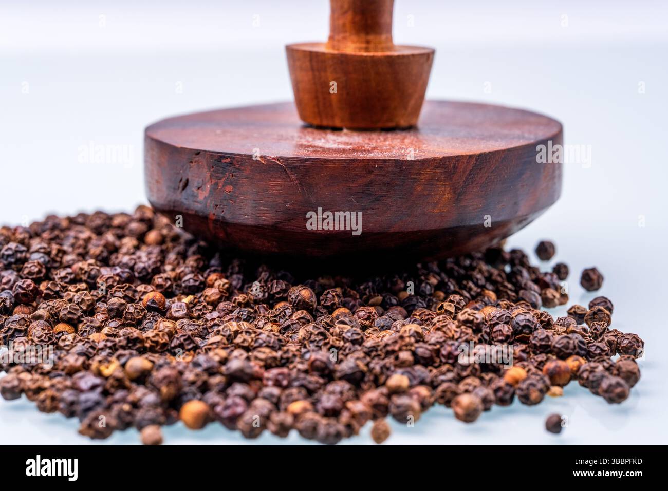 Macro close-up of black peppercorns (Piper nigrum) clustered beneath a ...