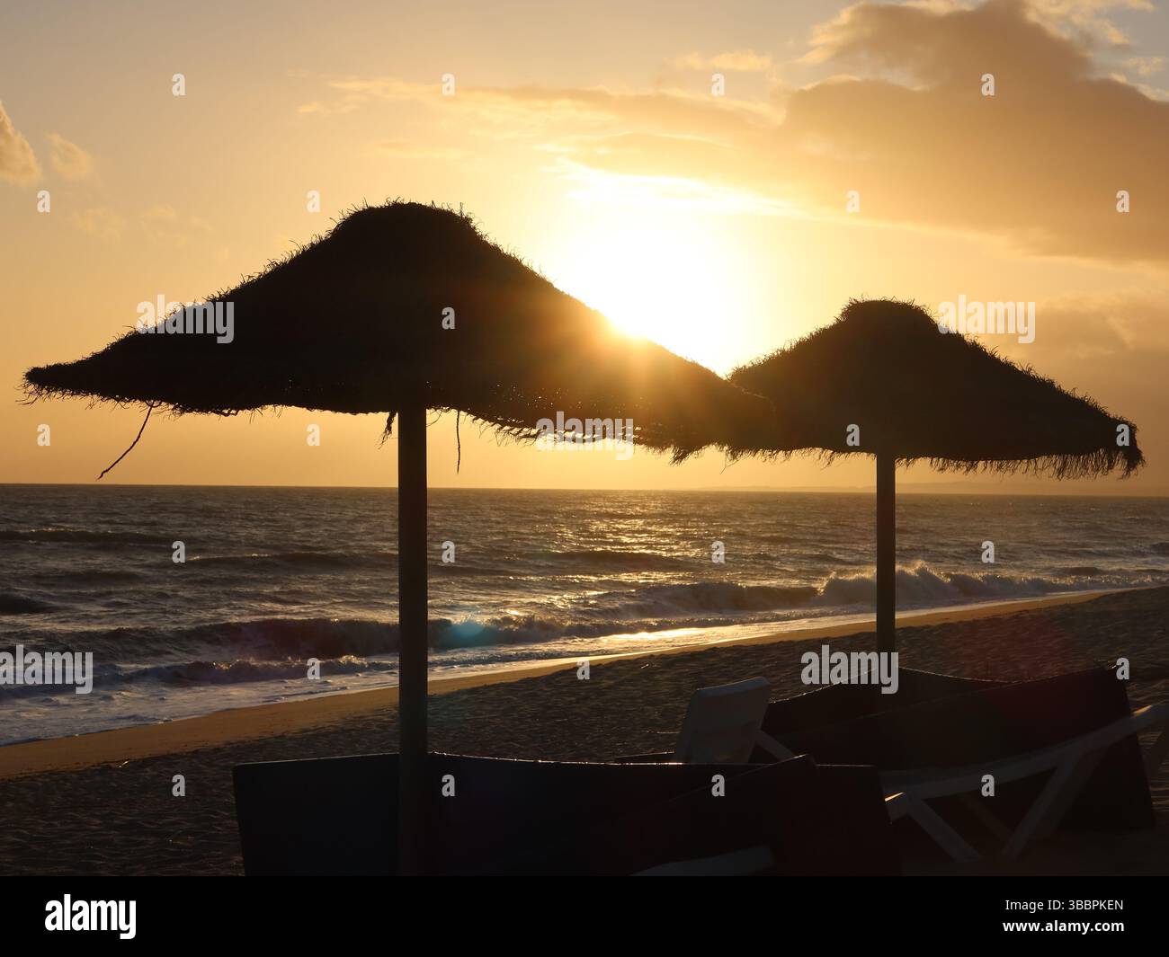 Romantic setting of two straw beach umbrellas & sun-loungers in front ...