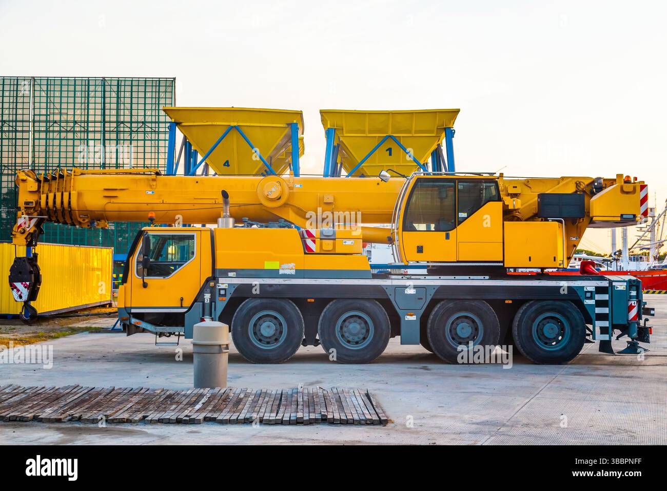 A yellow wheeled truck crane stands in the port. Heavy wheeled loading ...