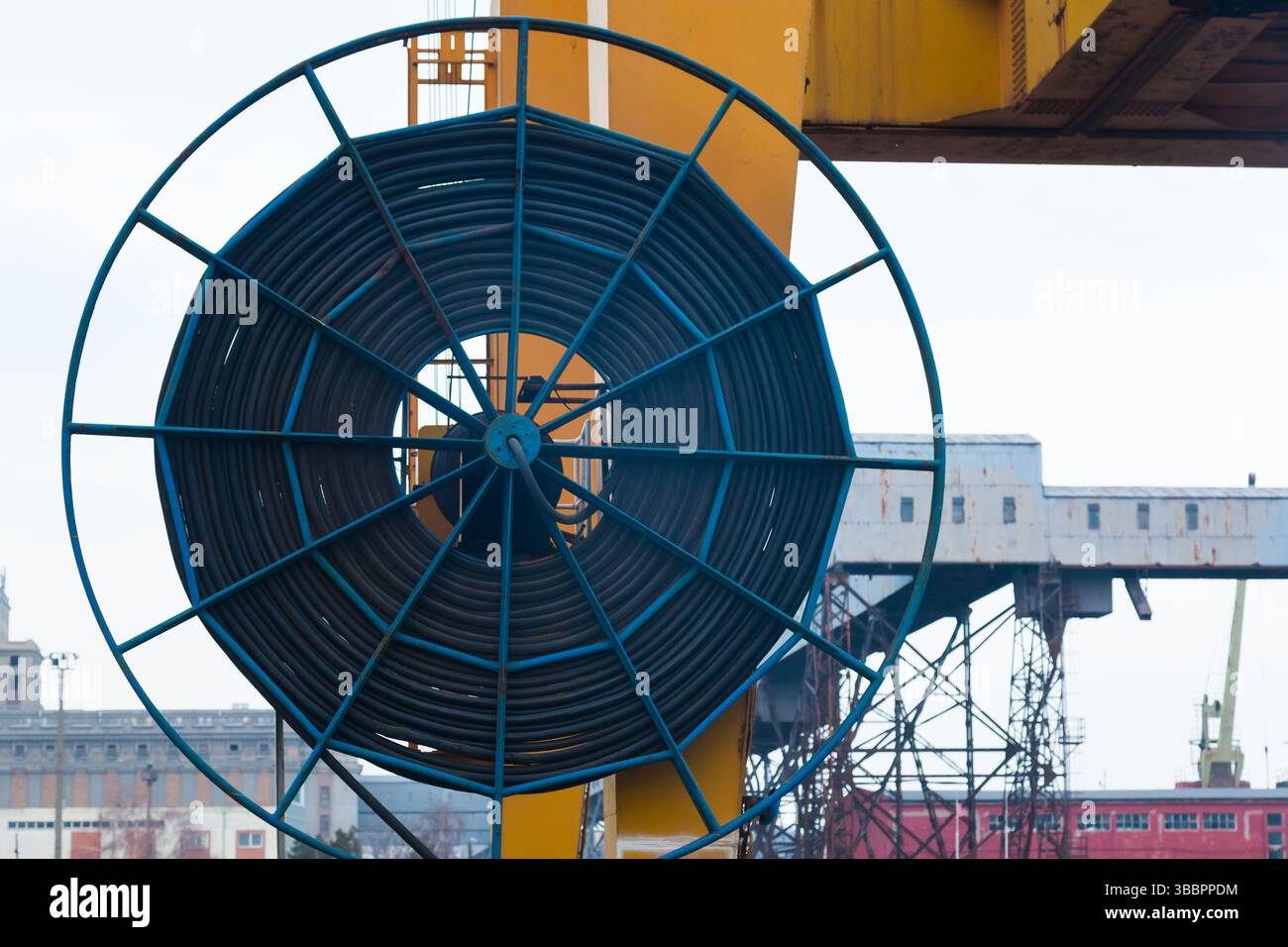 A large wheel with a harbor crane electric cable coiled around it in ...