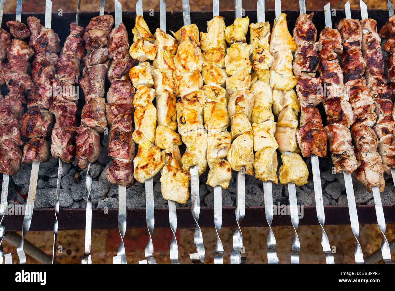 Three types of meat on skewers on the grill. Pieces of pork, chicken ...