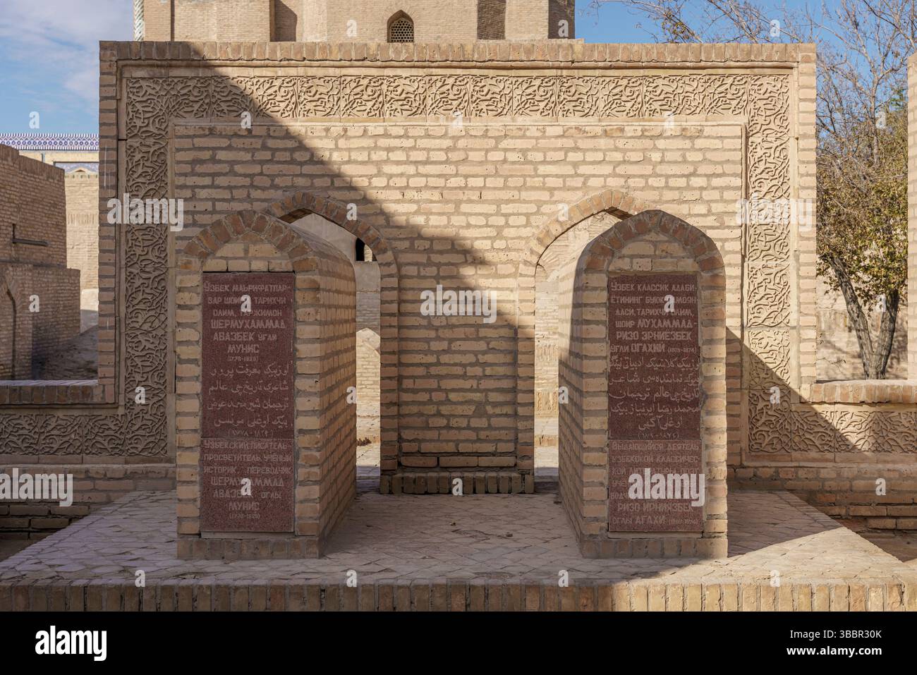 Two tall gravestones stand in front of the sandy brick facade of ...