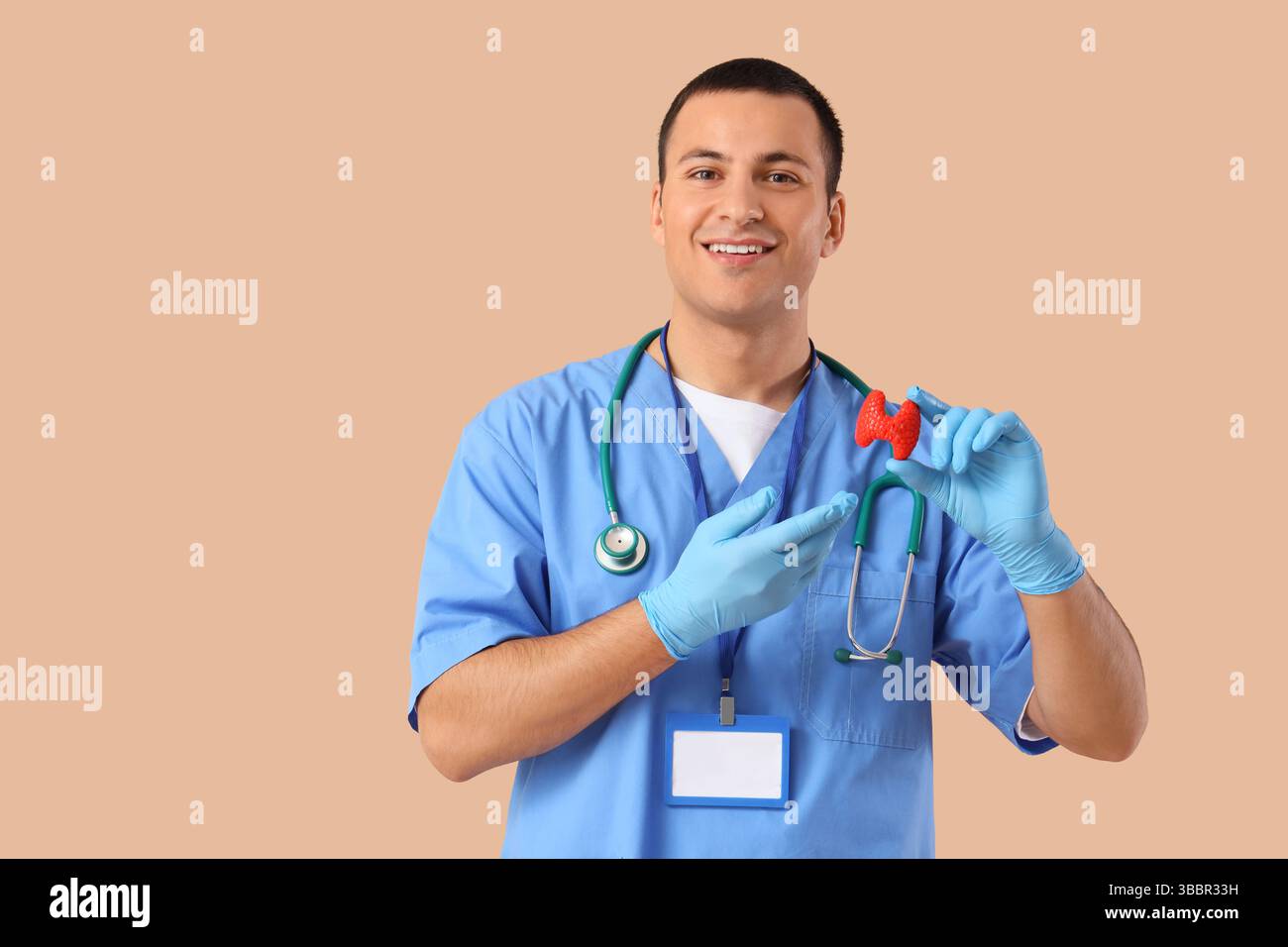 Male endocrinologist with thyroid gland model on beige background Stock ...