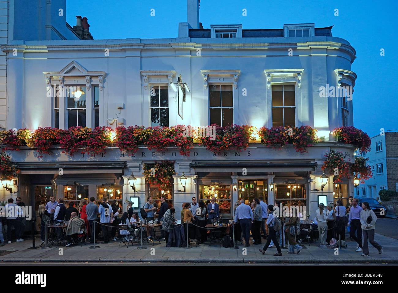 Outdoor pub tables on sidewalk on a summer night Stock Photo - Alamy