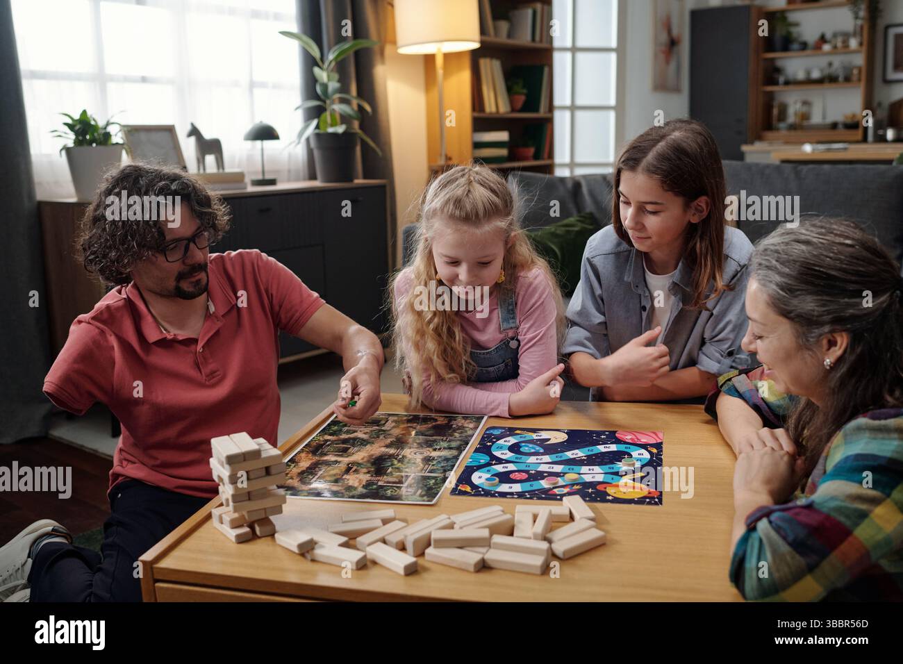 Family gathering around wooden table playing board games while enjoying ...