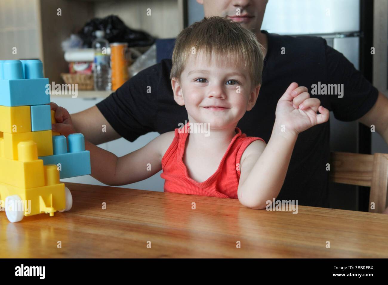 father and toddler son playing with plastic building blocks at home ...