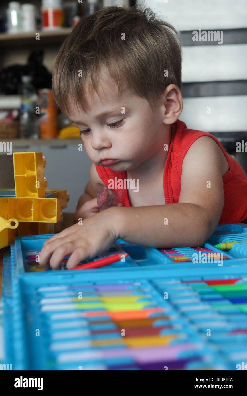 toddler boy playing with drawing kit at home , looking at colorful ...