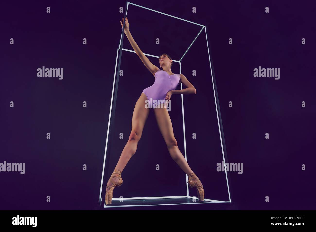 A ballerina in a photo studio on a black background in a light led cube ...