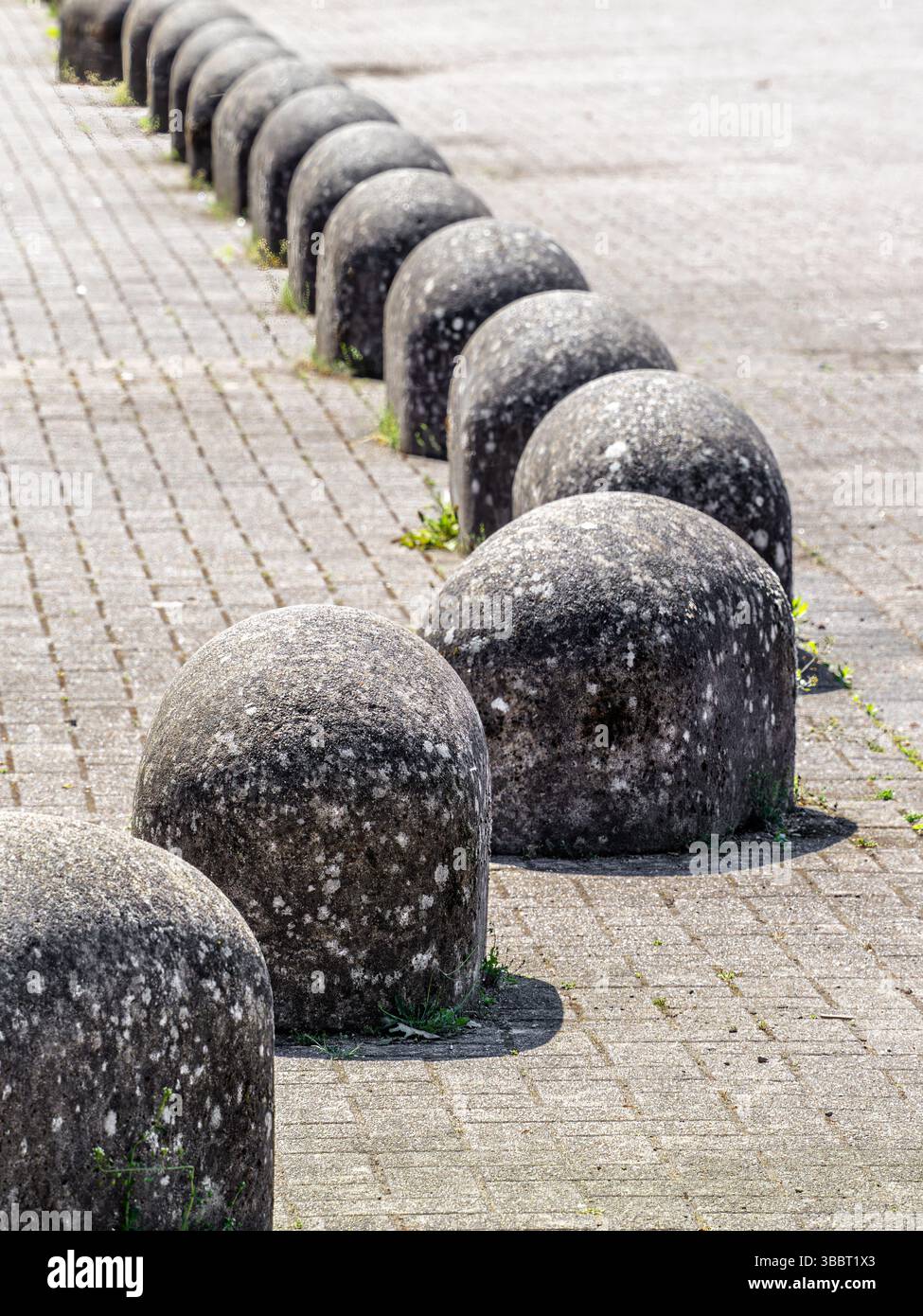 A row of rounded stone bollards on a paved surface, showcasing ...