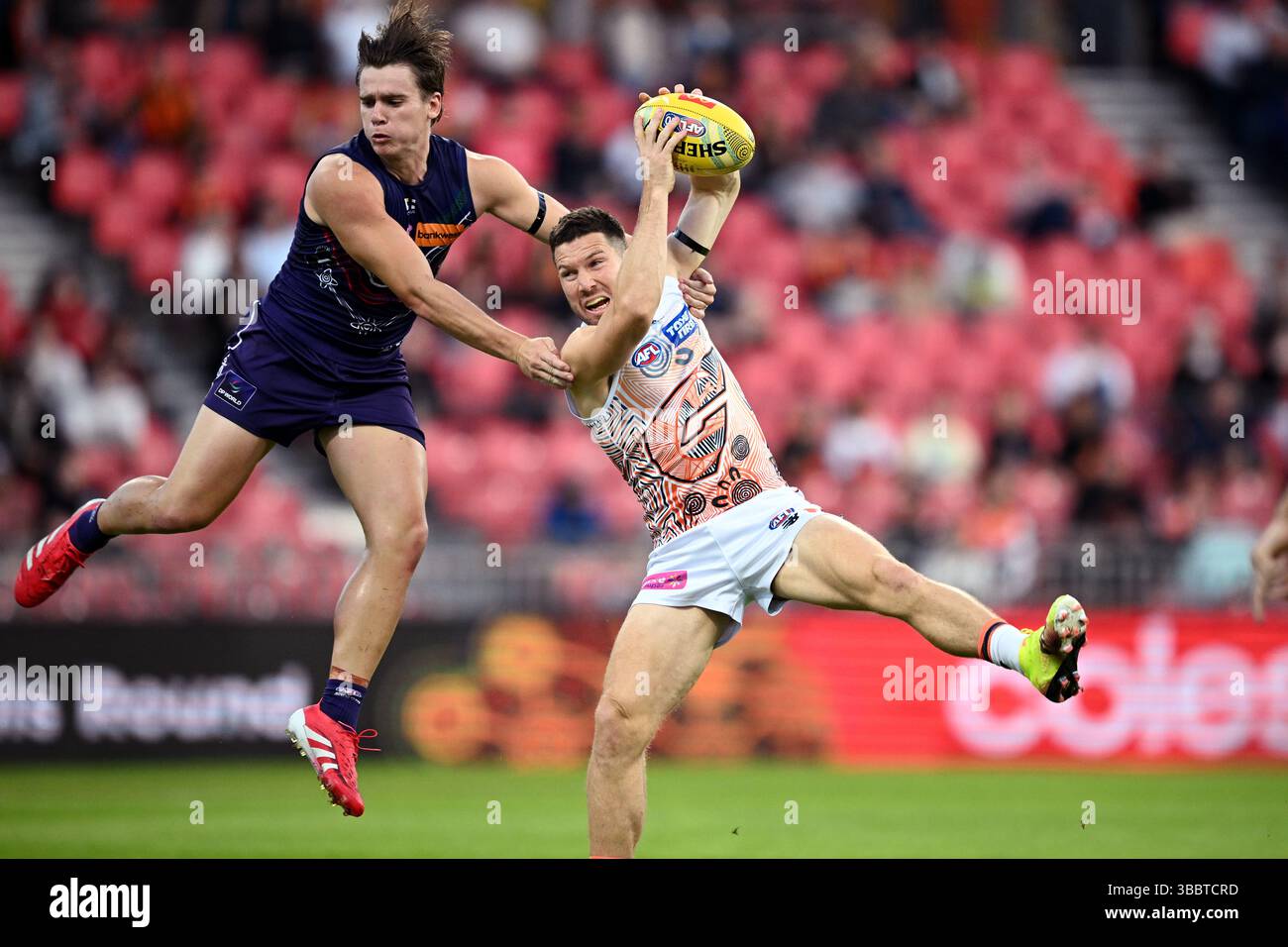 Toby Greene of the Giants takes a mark over Caleb Serong of the Dockers ...