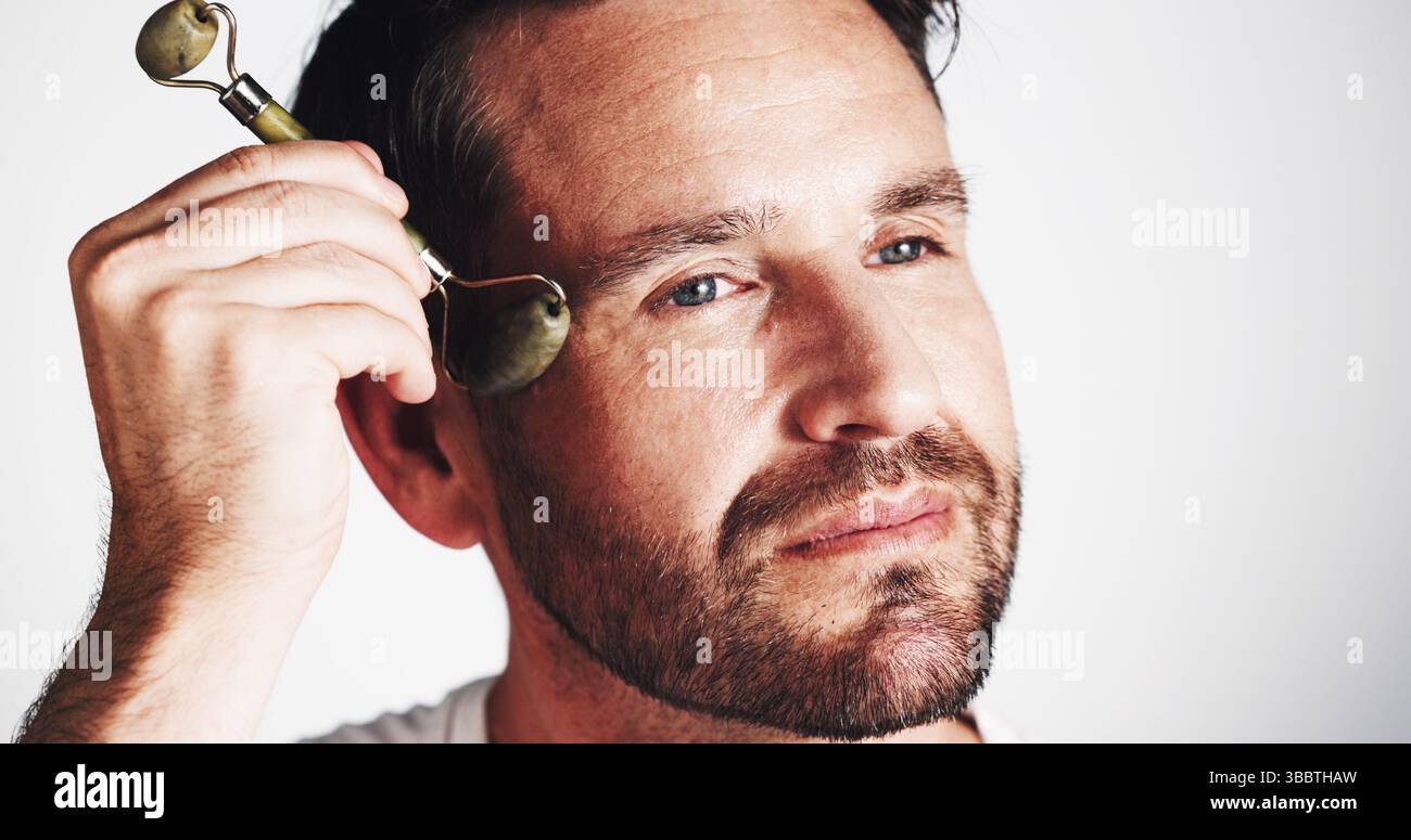 Studio, glow and man with roller, skincare and facial treatment to ...