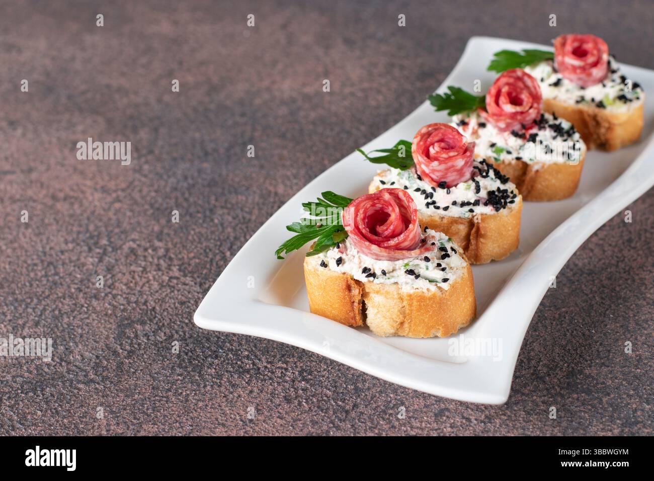 Canapes with cream cheese and sausage on bread toast in white plate ...