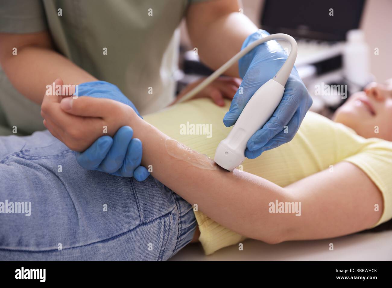 Sonographer conducting ultrasound examination of girl's arm in clinic ...