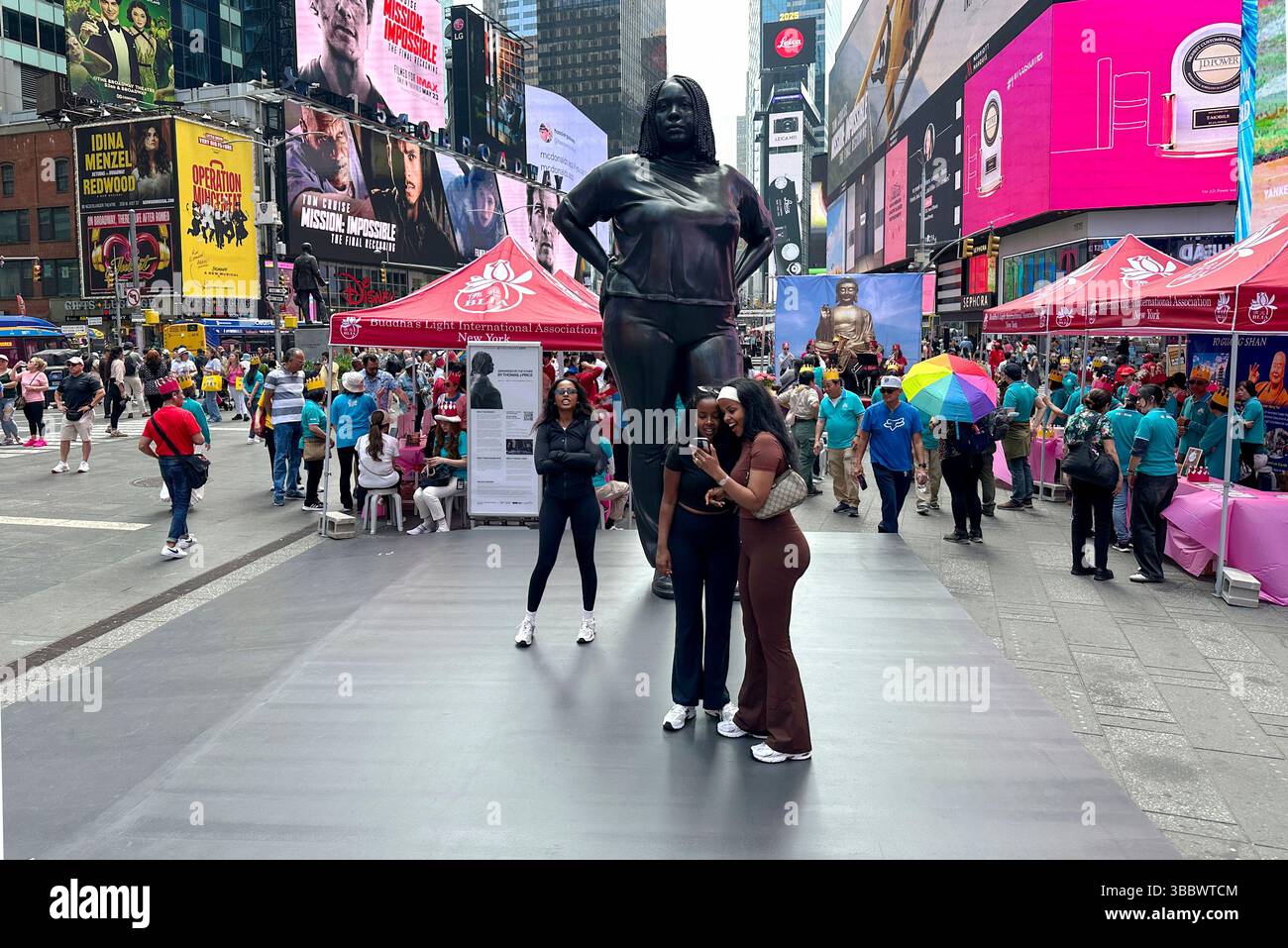 Women pose for photographs with the 12-foot-tall bronze sculpture ...