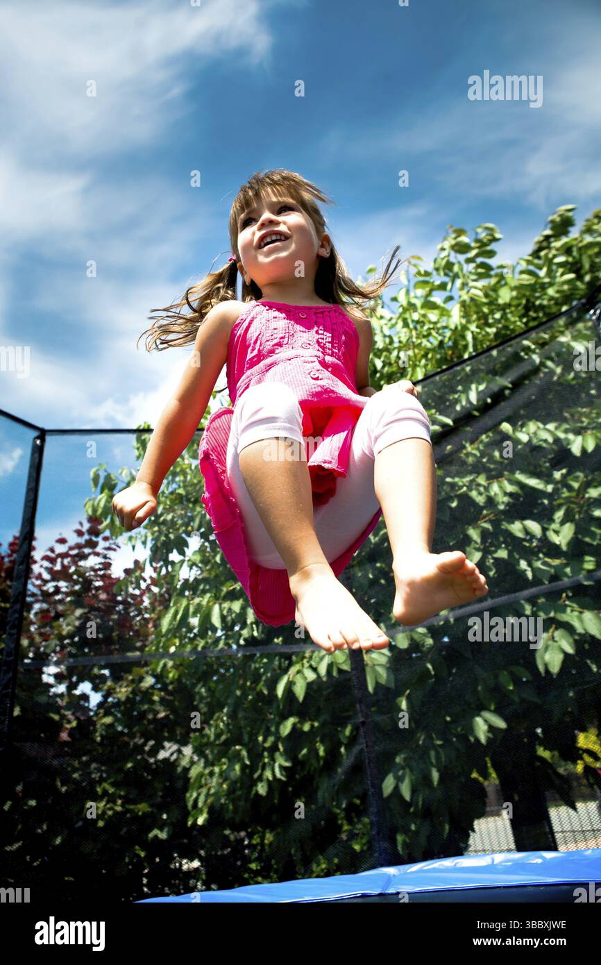 Little girl jumping on the trampoline Stock Photo - Alamy
