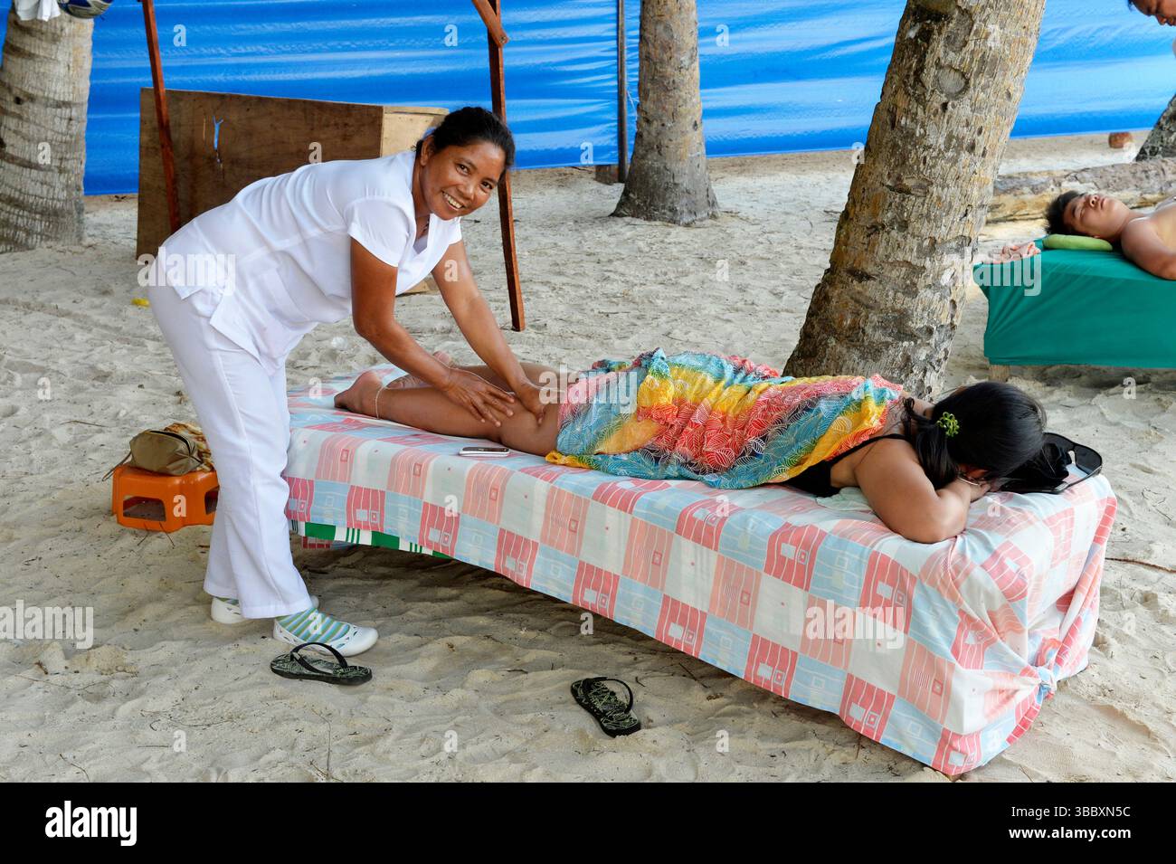Tourist receiveing beach massage from philippina woman on Alona beach ...