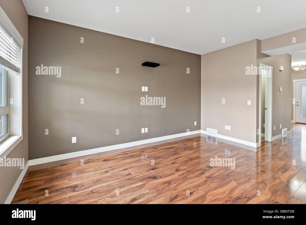 Large, empty room with a tan wall and wooden floors. The room is large ...
