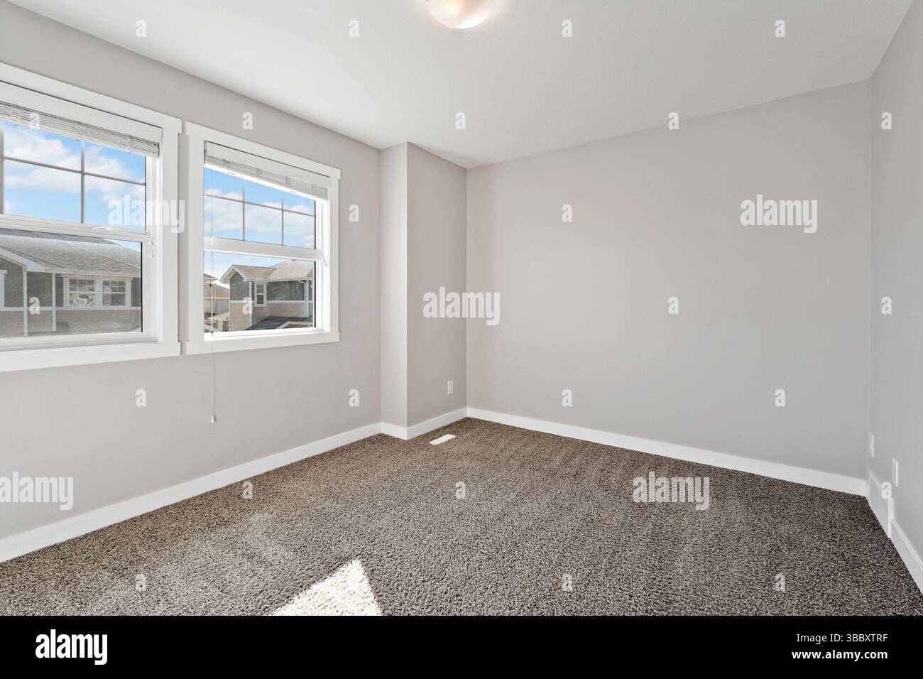 Very clean and empty room with a tan wall and tan carpet. The room has ...