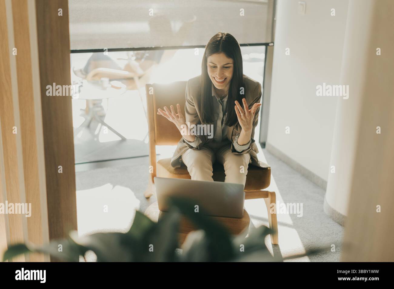 Joyful young woman beams at her laptop during a video call Stock Photo ...