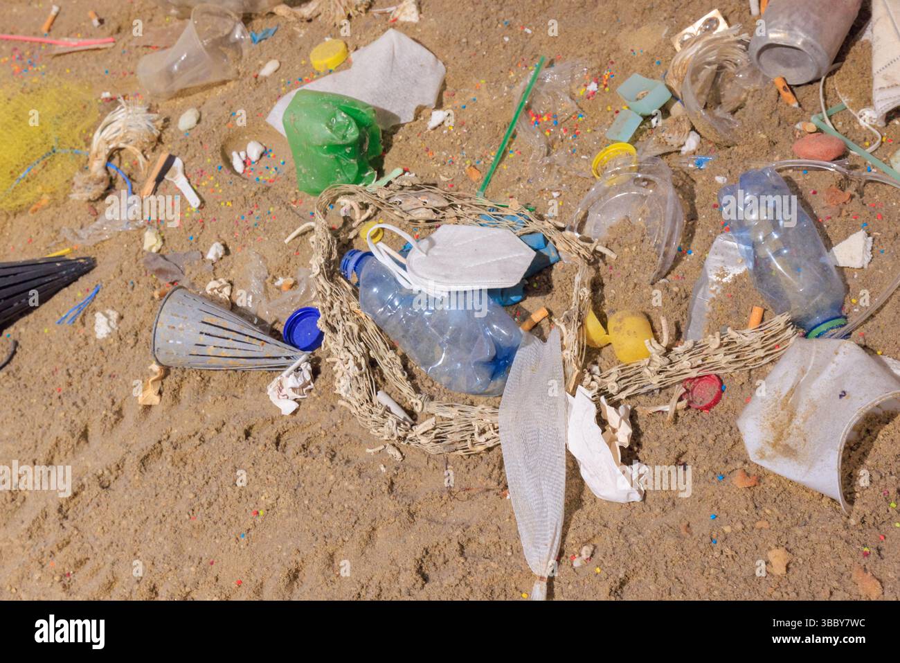 Plastic bottles, wrappers, and debris litter the sandy beach. This ...